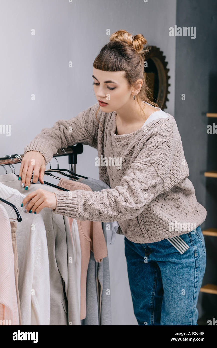 girl standing near stand and choosing what to wear Stock Photo - Alamy
