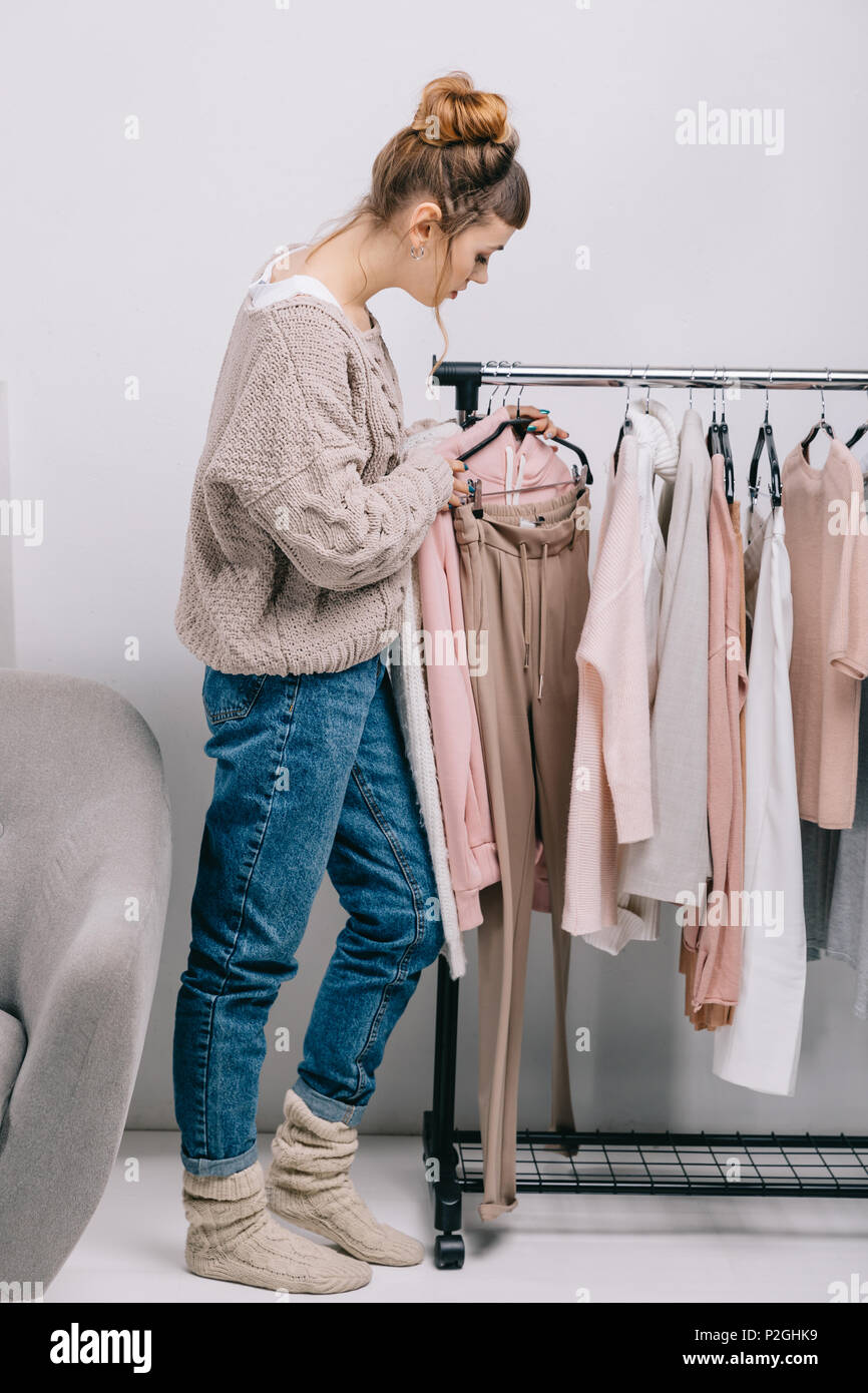 side view of girl standing near stand and choosing what to wear Stock ...