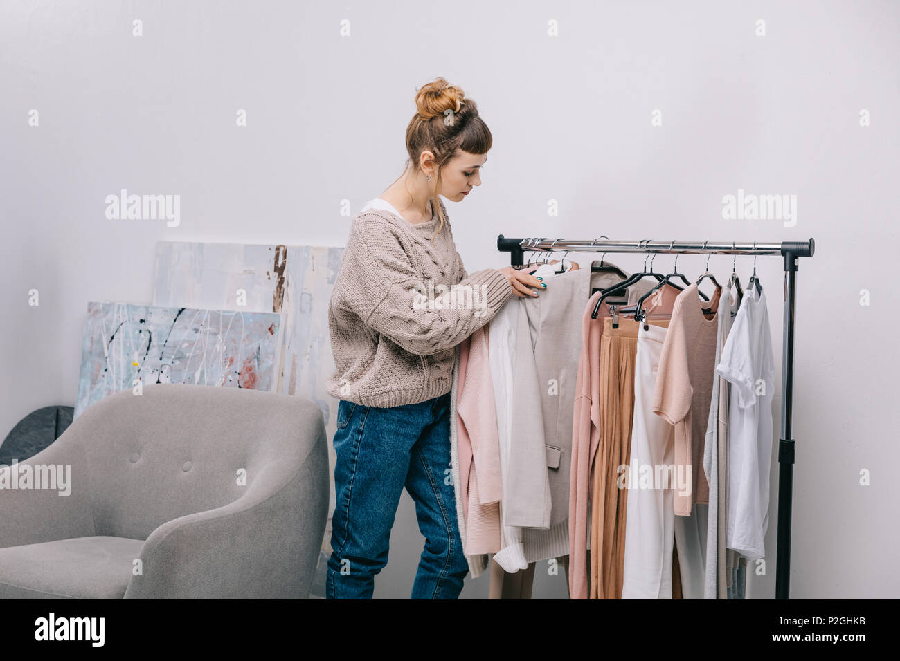 girl standing near stand and choosing what to wear Stock Photo - Alamy