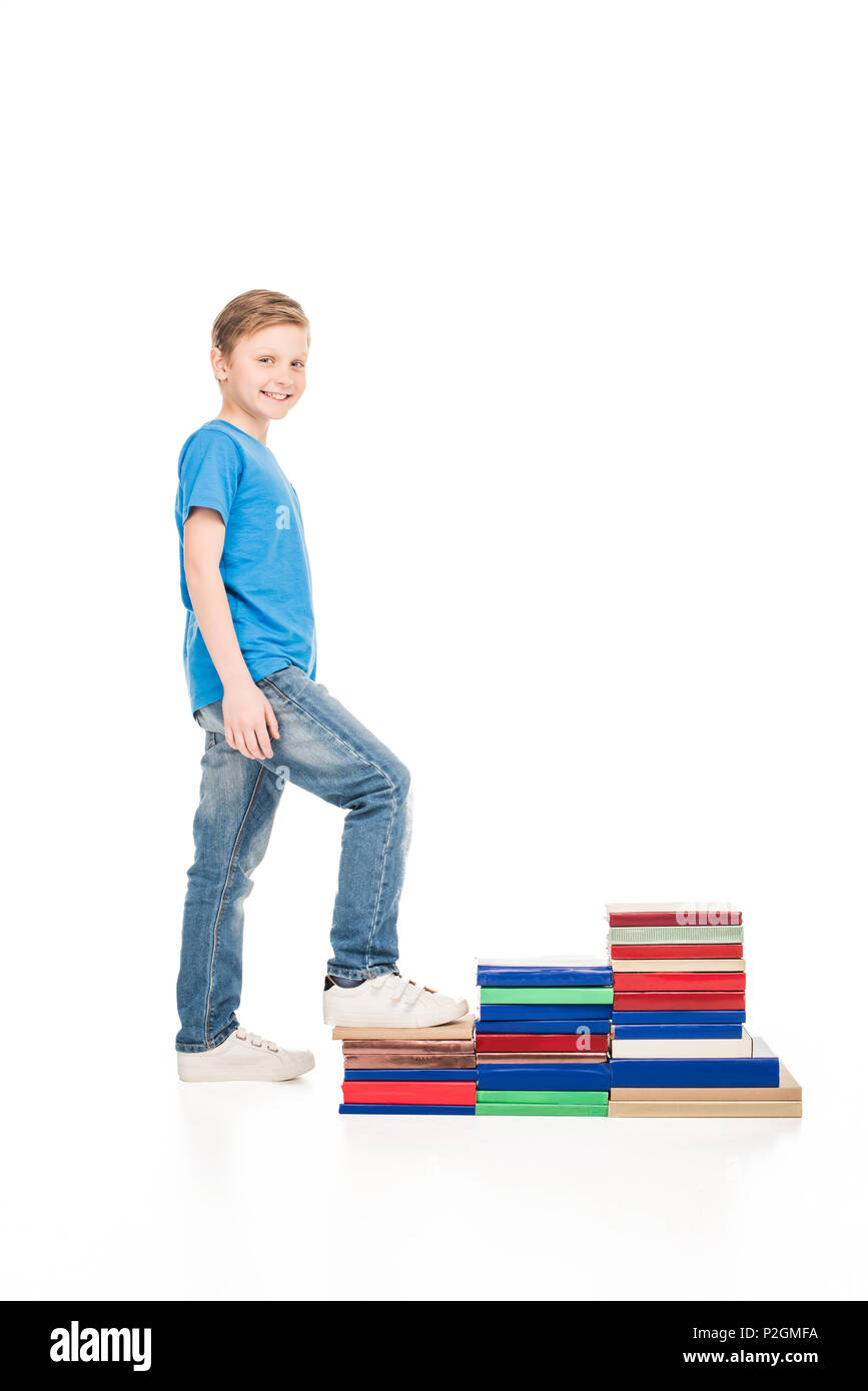 cute little boy stepping on books and smiling at camera isolated on ...