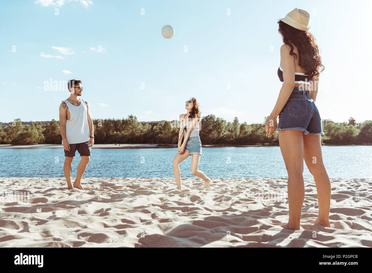 group of active friends playing volleyball on beach together Stock ...