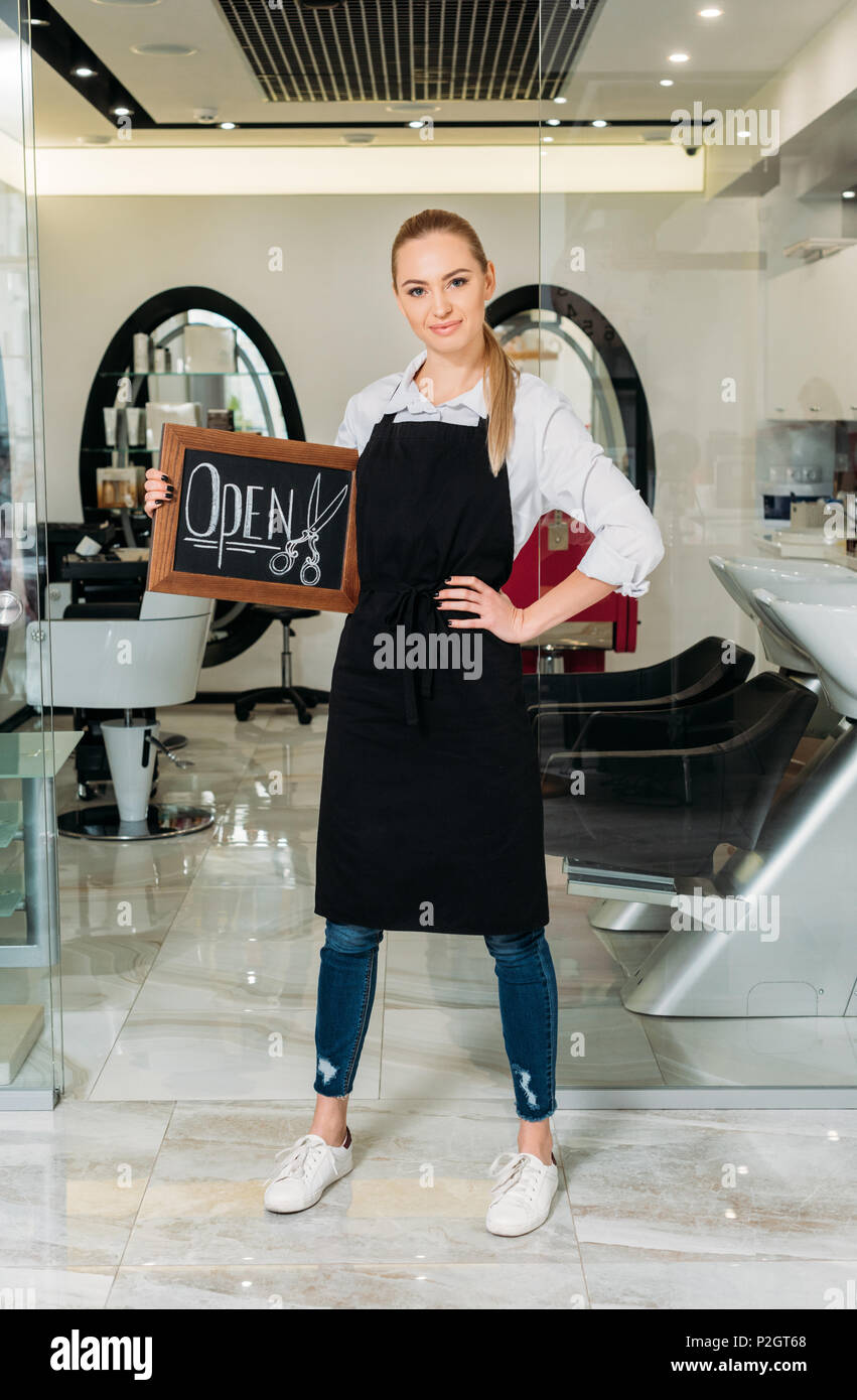 blonde owner of salon standing with sign open Stock Photo - Alamy