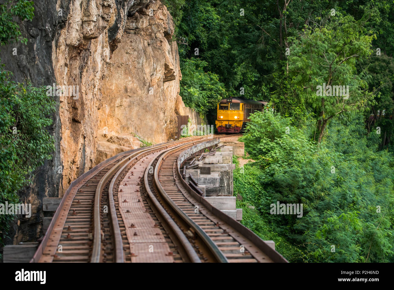 Old railroad tracks on bridge beside cliff rock, focus on railroad ...