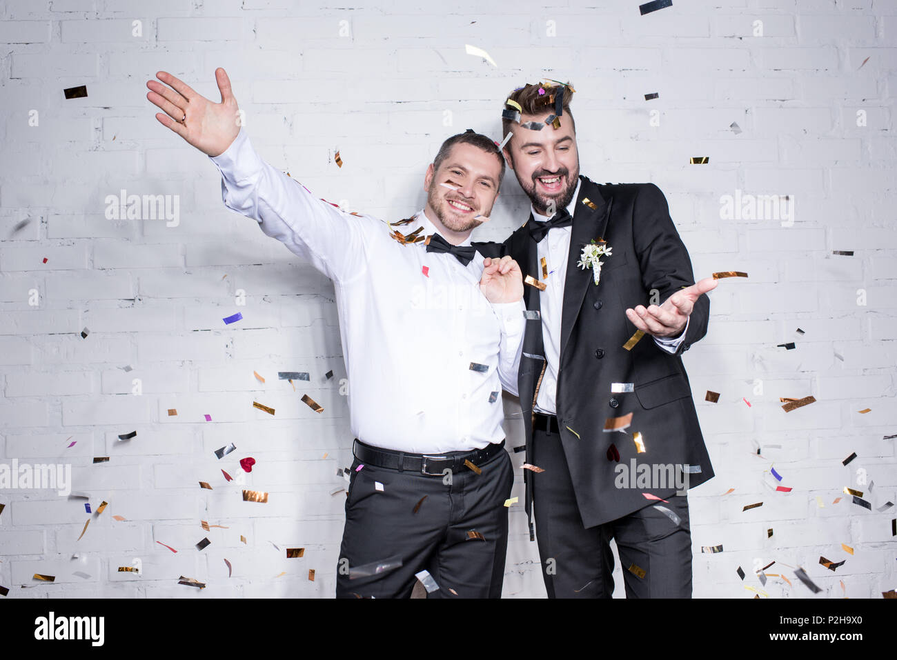 happy homosexual couple in suits smiling and celebrating wedding with ...