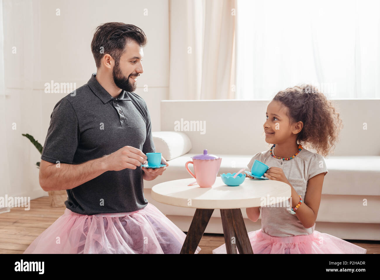 multicultural father and little daughter having tea party at home Stock ...