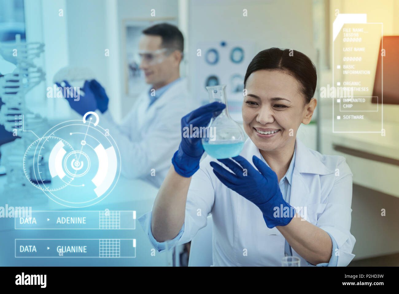 Happy scientist smiling while looking at the blue liquid Stock Photo ...