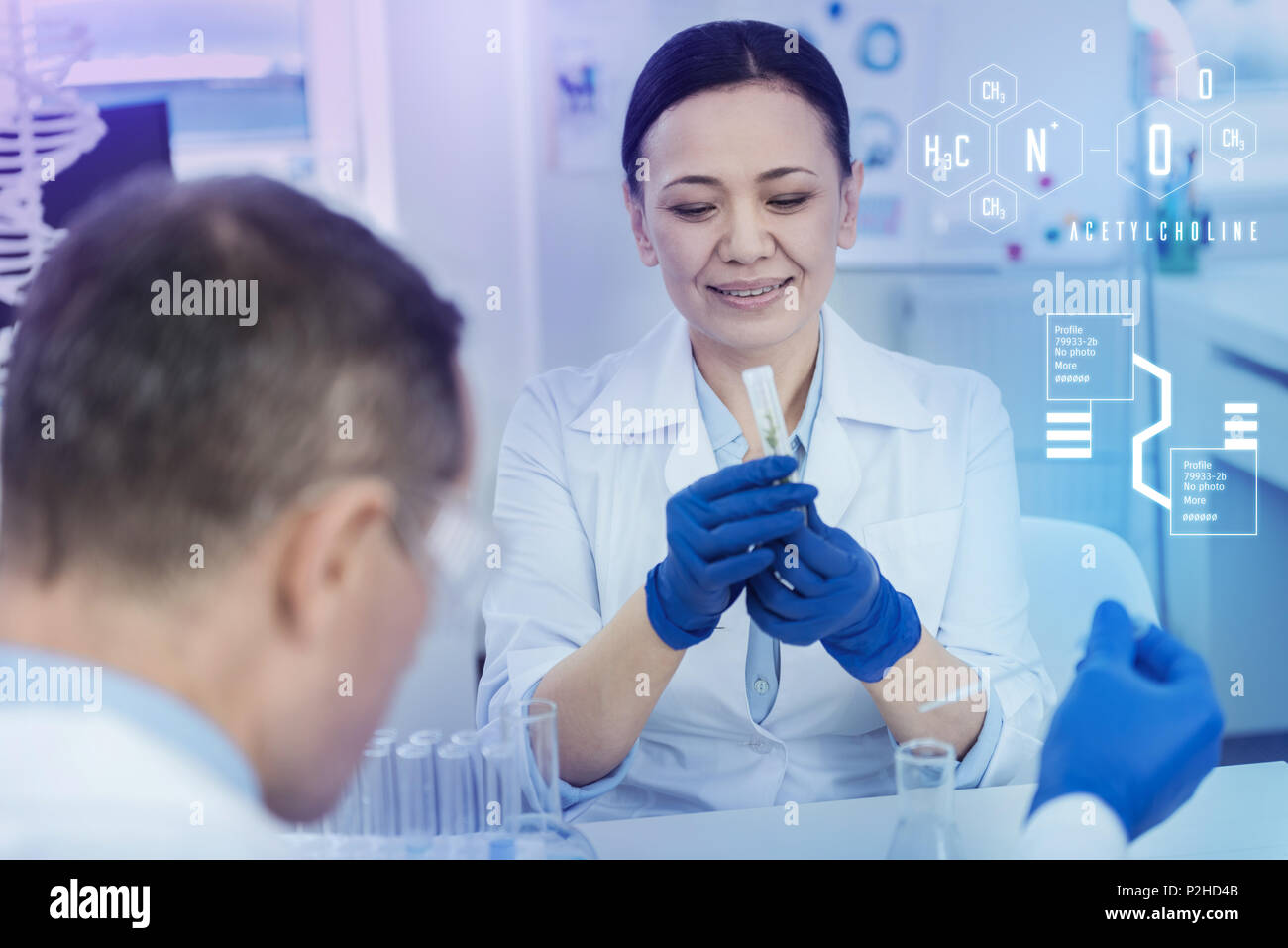 Calm biologist smiling while looking at the herb in a test tube Stock ...