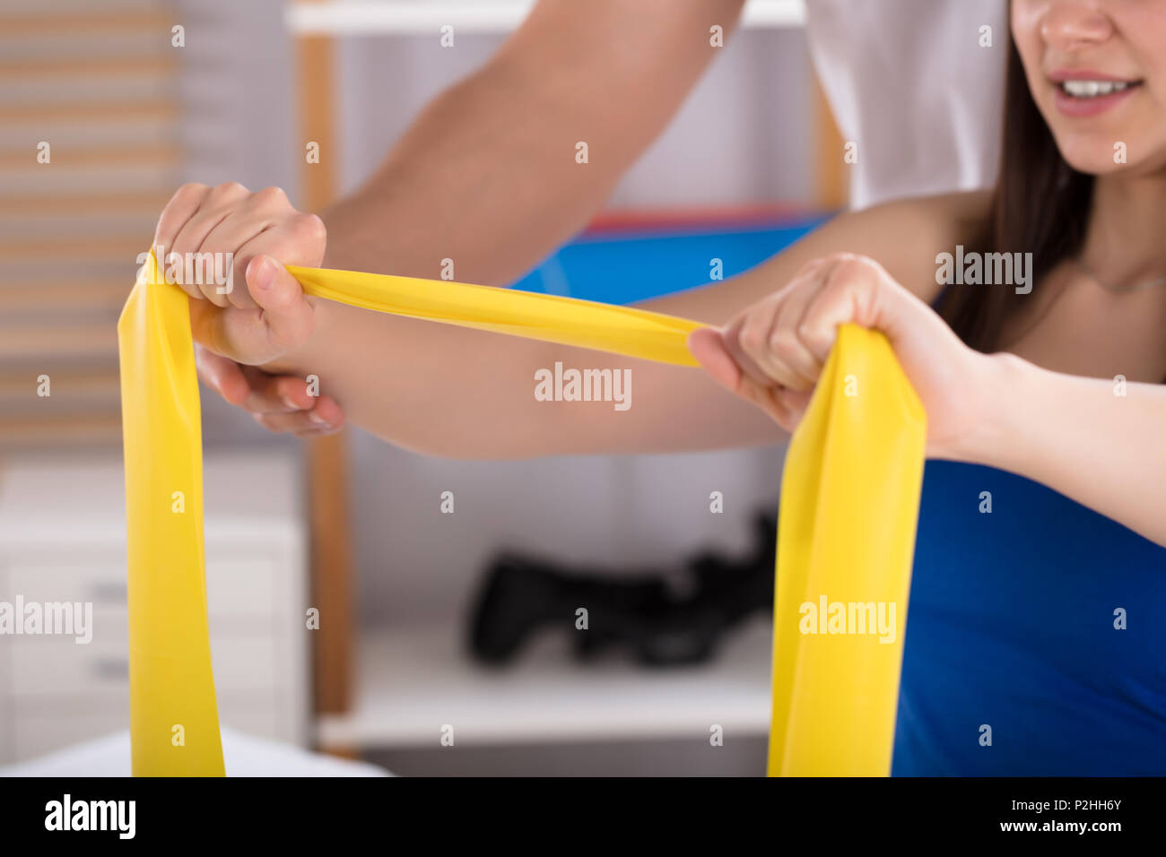 Physiotherapist Assisting Woman While Doing Exercise With Yellow ...