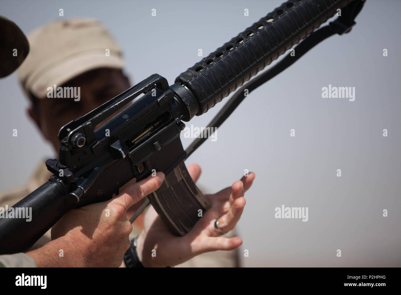 A Spanish trainer ensures that an M16 rifle magazine is loaded properly ...
