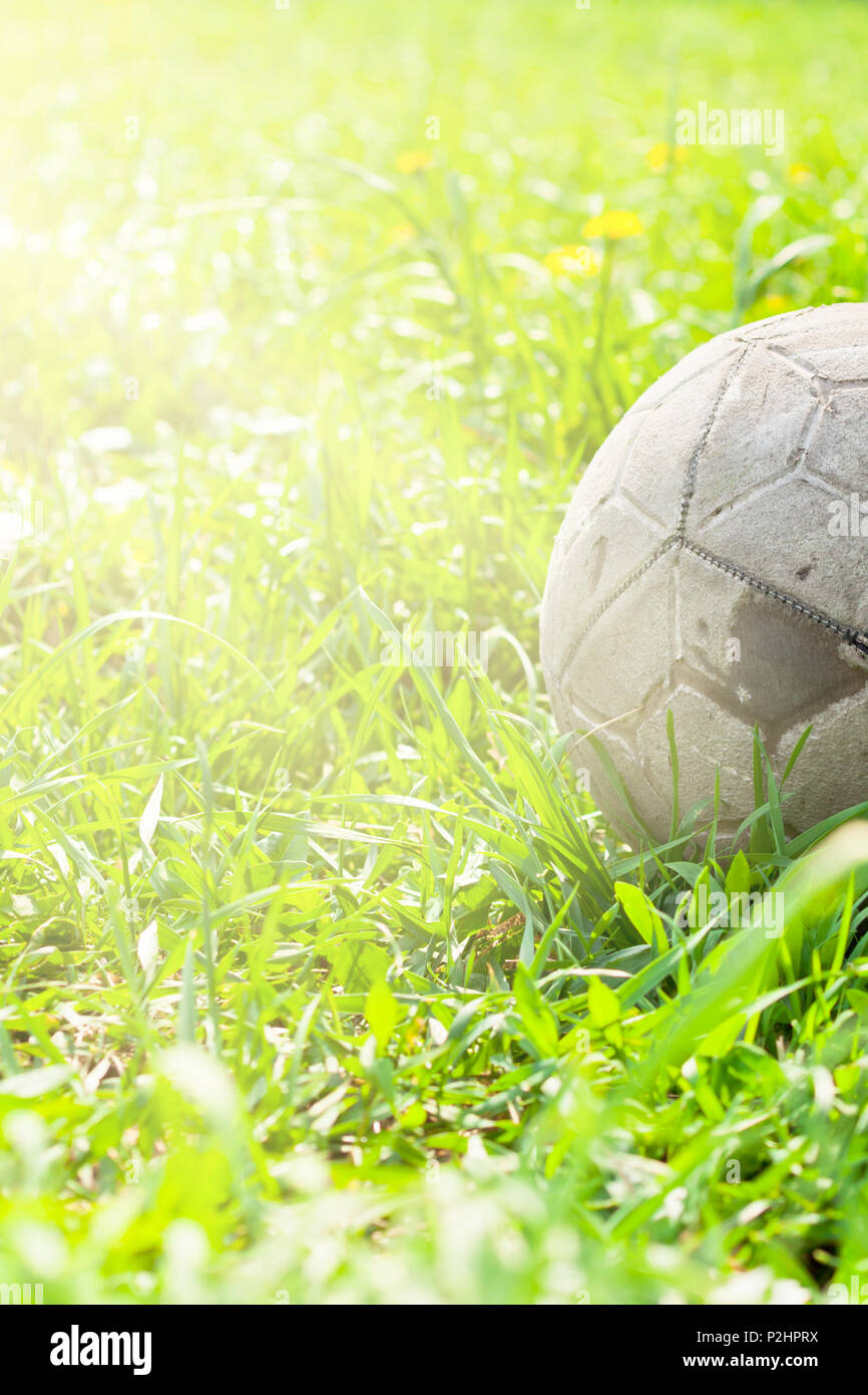 Old soccer ball forgotten in the green grass field. The football ...