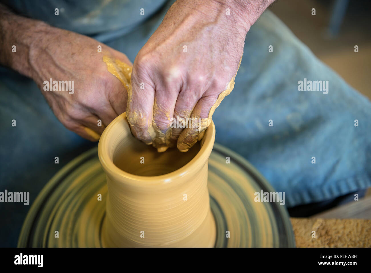clay being shaped on a rotating pottery wheel by the potter in the ...