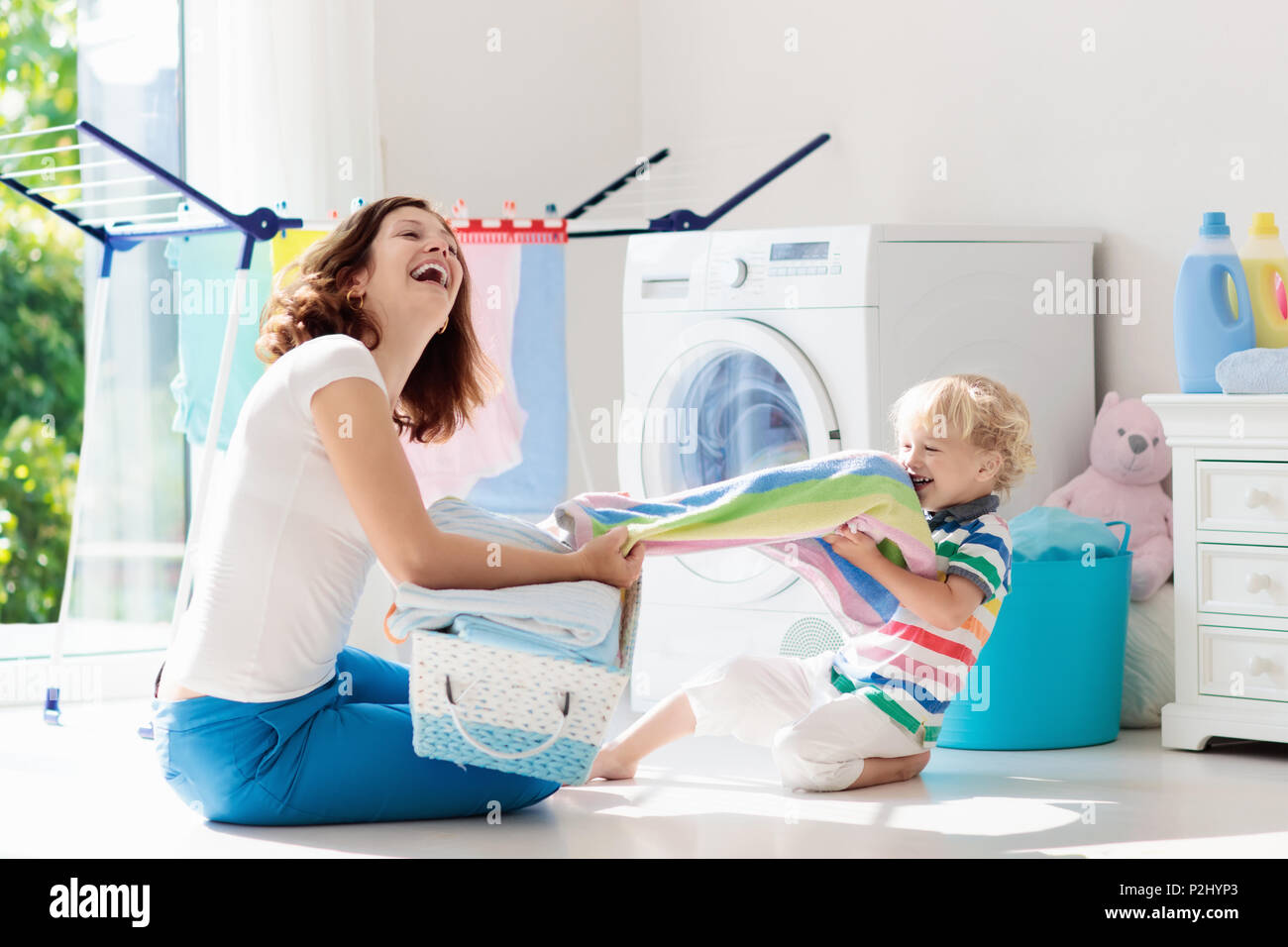 Mother and kids in laundry room with washing machine or tumble dryer ...