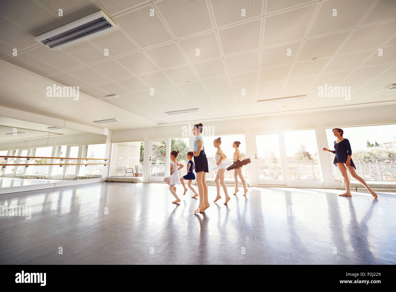 Young elegant small girls dancing ballet while teacher watching in ...