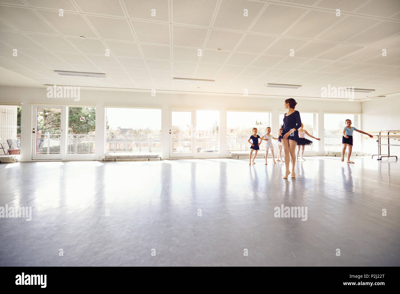 Female teacher showing a dance to the little ballerinas in ballet class ...