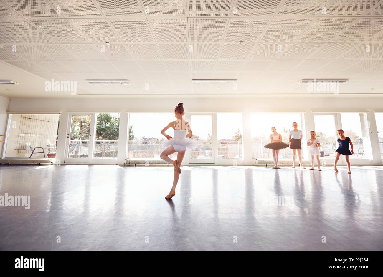 Young ballerina performing dance in ballet class while group watching ...