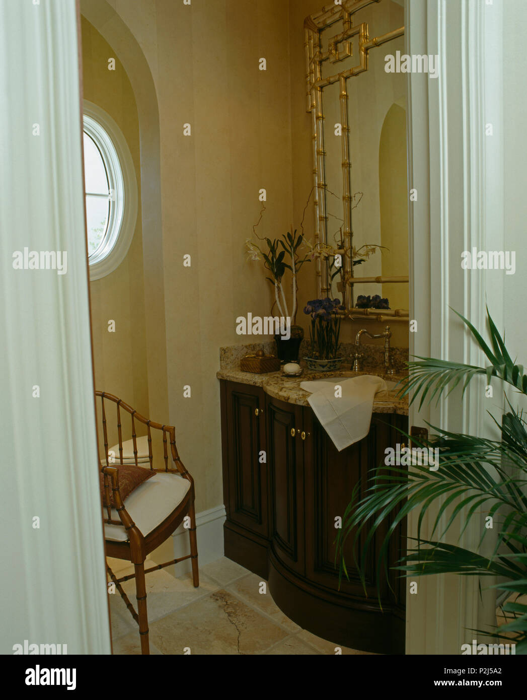Gilt-framed mirror above basin in vanity unit in corner of traditional ...