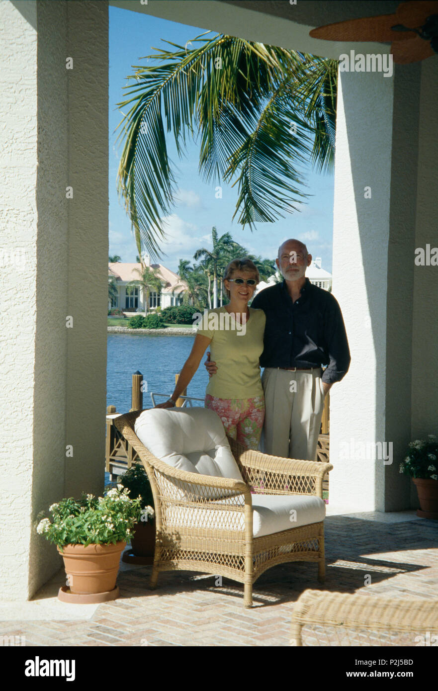 Portrait of middle-aged couple standing on waterside veranda FOR ...