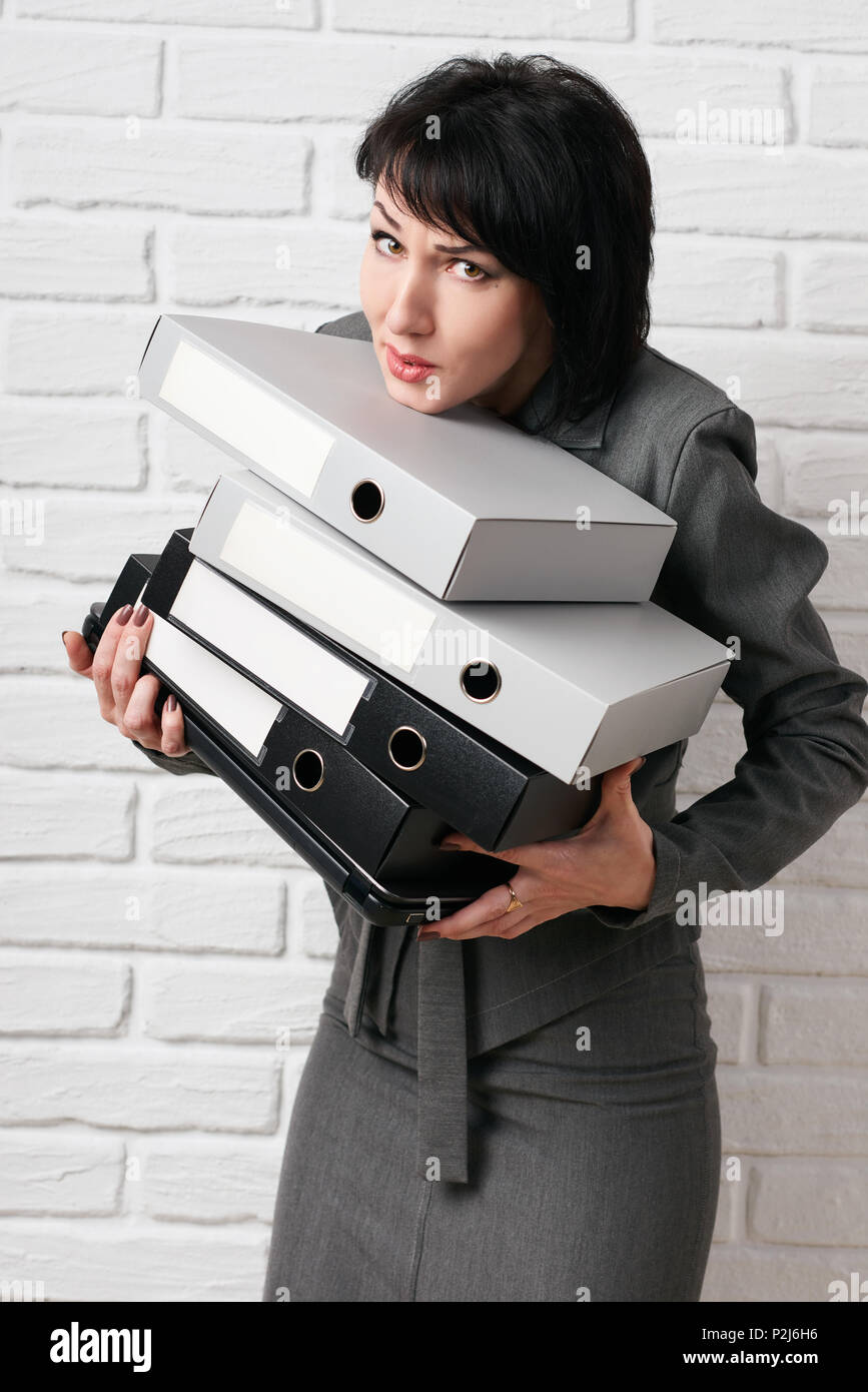 business woman with folder, dressed in a gray suit poses in front of a ...