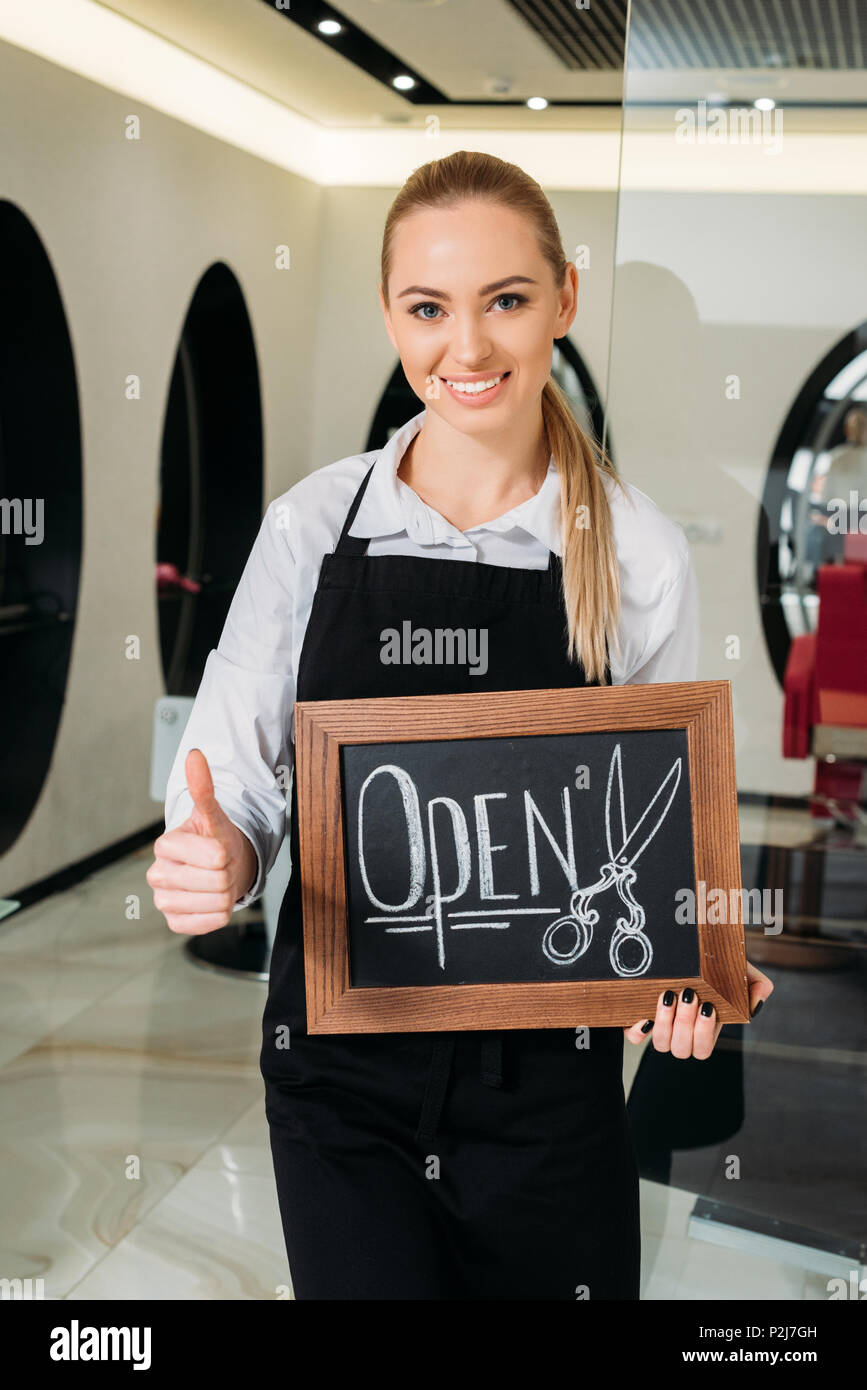 smiling hairdresser holding signboard open and showing thumb up Stock ...