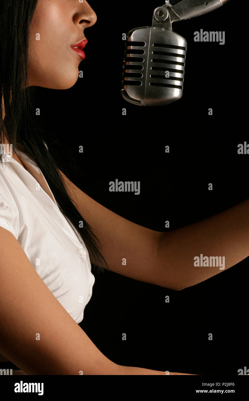 young woman singing into a mic Stock Photo - Alamy