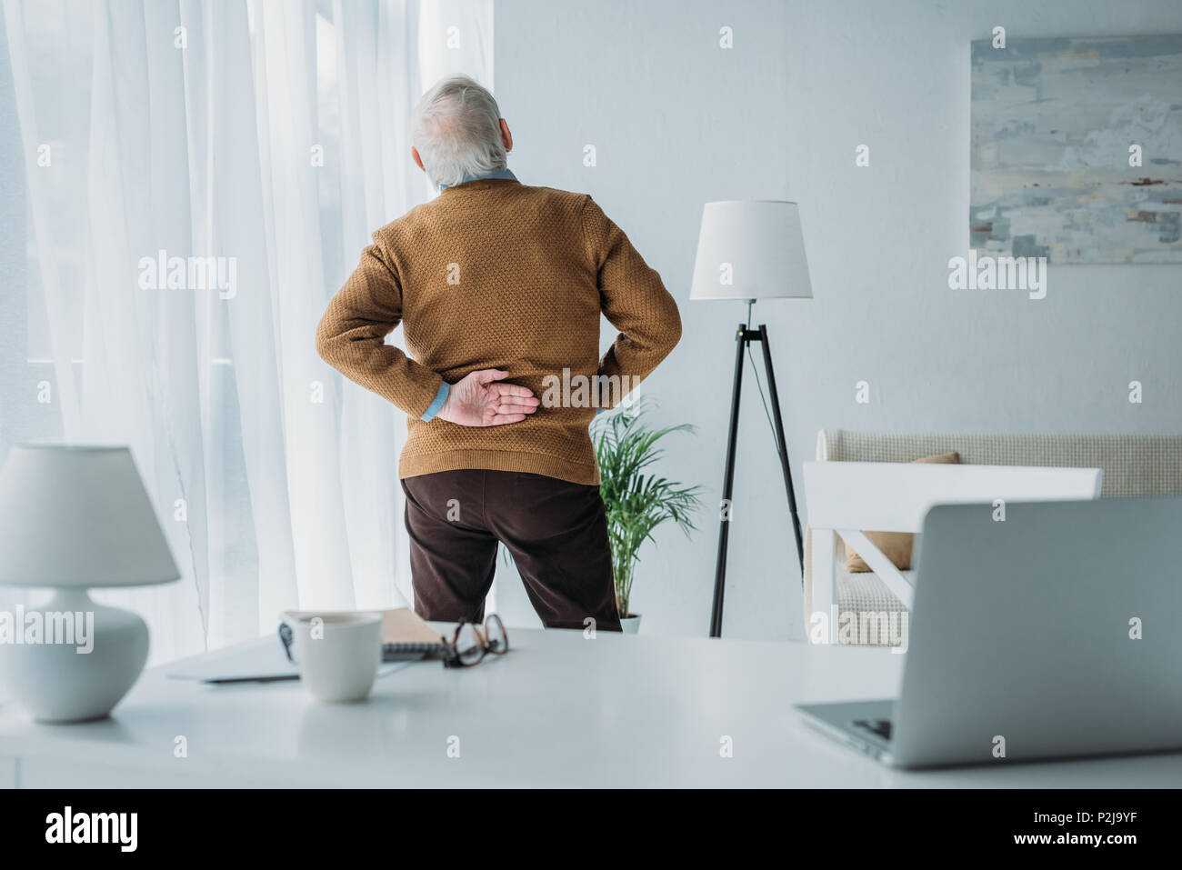 Senior man suffering from back pain during work in office Stock Photo ...