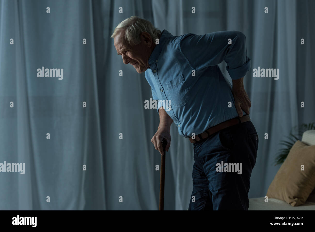 Senior man suffering from back pain leans on a cane Stock Photo - Alamy