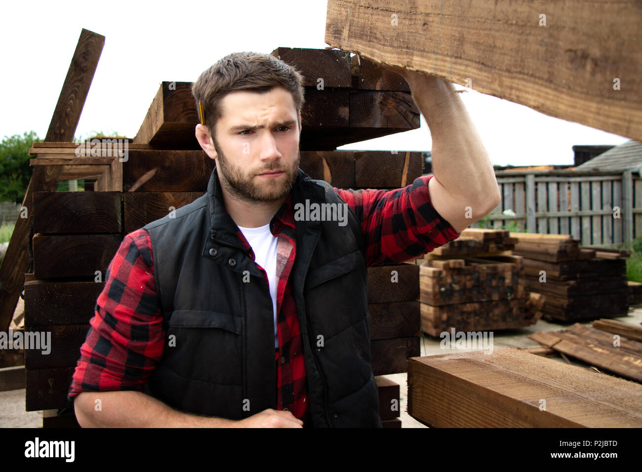 Carpenter, Yard worker, labourer, laborer with tool belt carries long ...