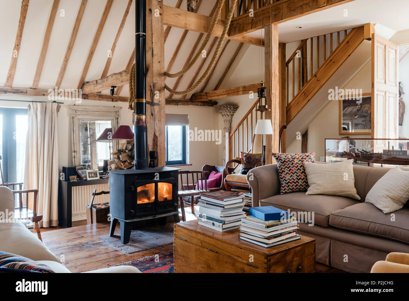 Lit woodeburner with books on travelling chest in Sussex barn ...