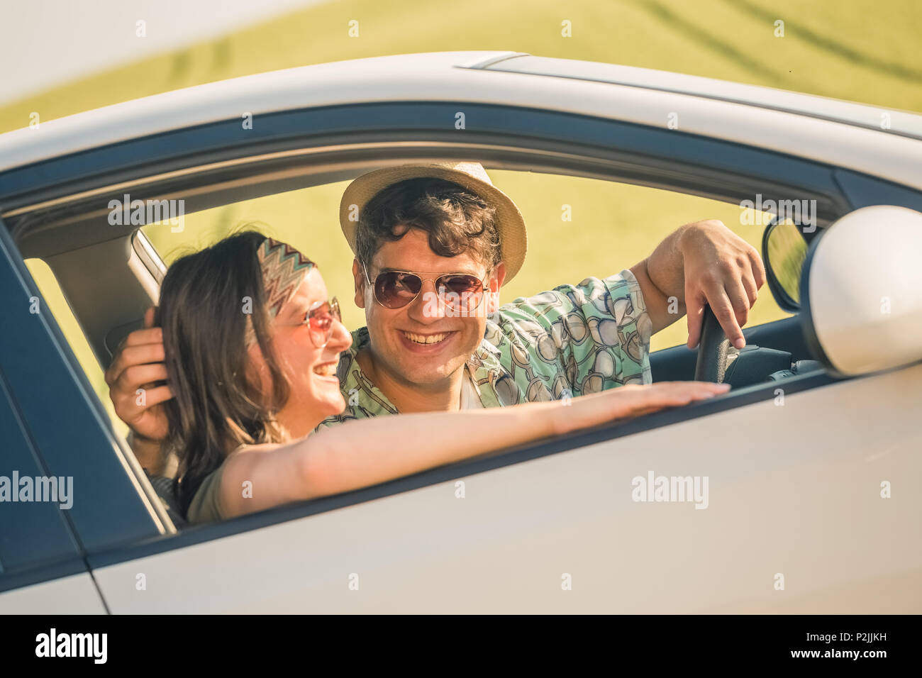 Side view of beautiful couple in car on their summer vacation road trip ...