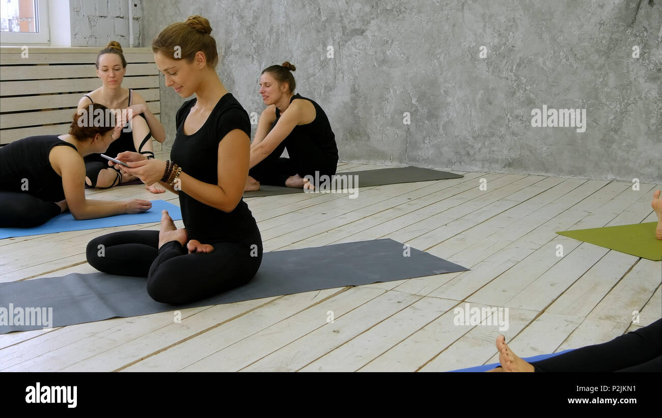 Fit women looking at digital table chatting in bright exercise room ...