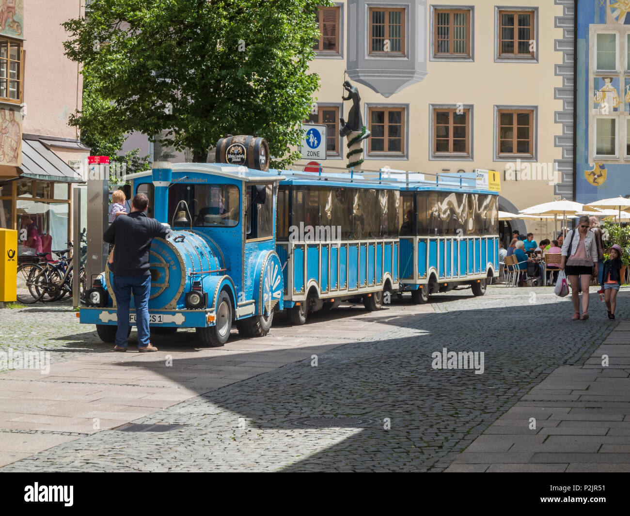 Blue city tour train with tractor and two trailers at the stop. City ...