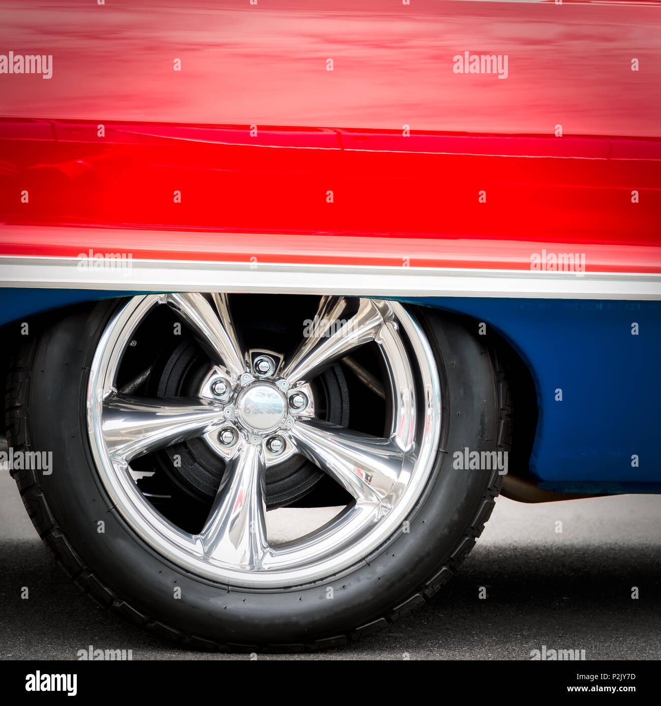 A classic American car, with updated hubcaps, from the sixties in red ...