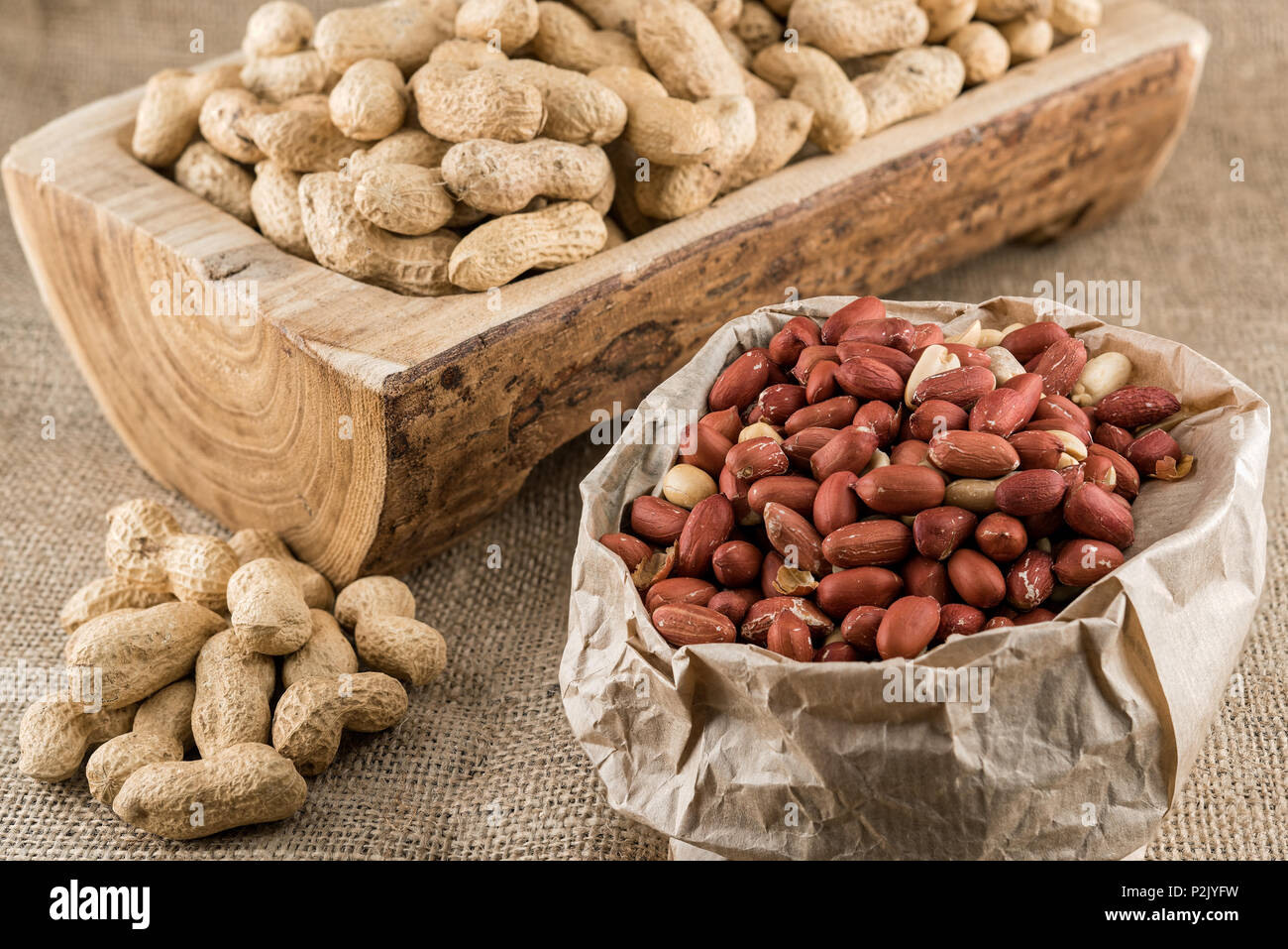 Paper bag full of peeled peanuts and peanuts in nutshell on a piece of ...