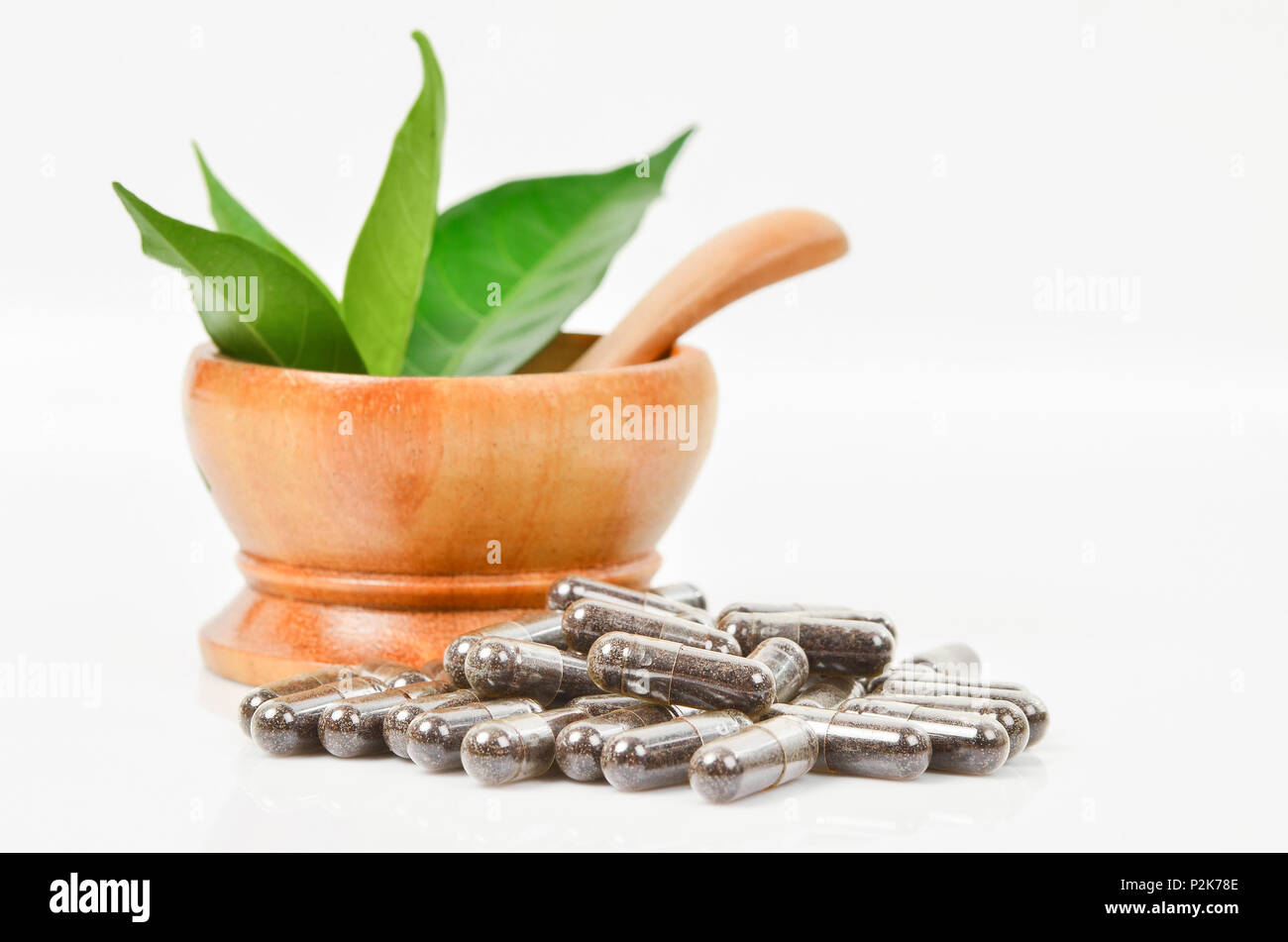 Natural medicine capsule pill with black herb, and wooden mortar on ...