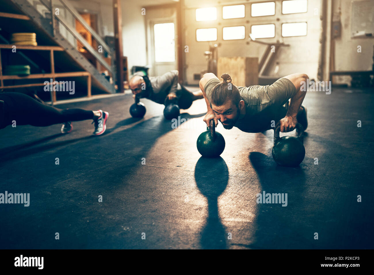 Fit young man doing pushups on dumbbells while working out during an ...