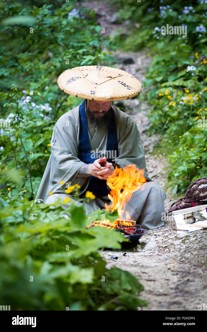 European man with beard and japanese robe makes fire ceremony in front ...