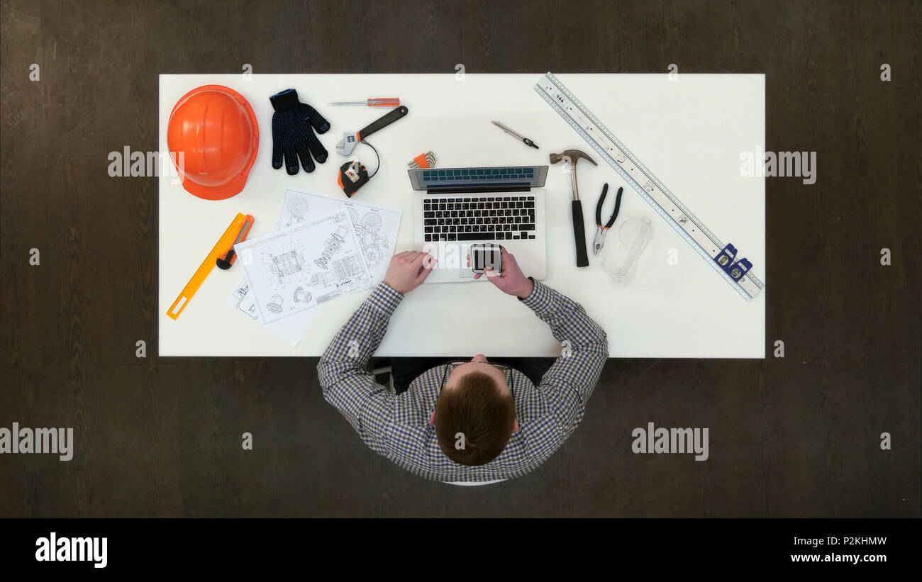 Office engineer using mobile phone sitting at his desk Stock Photo - Alamy