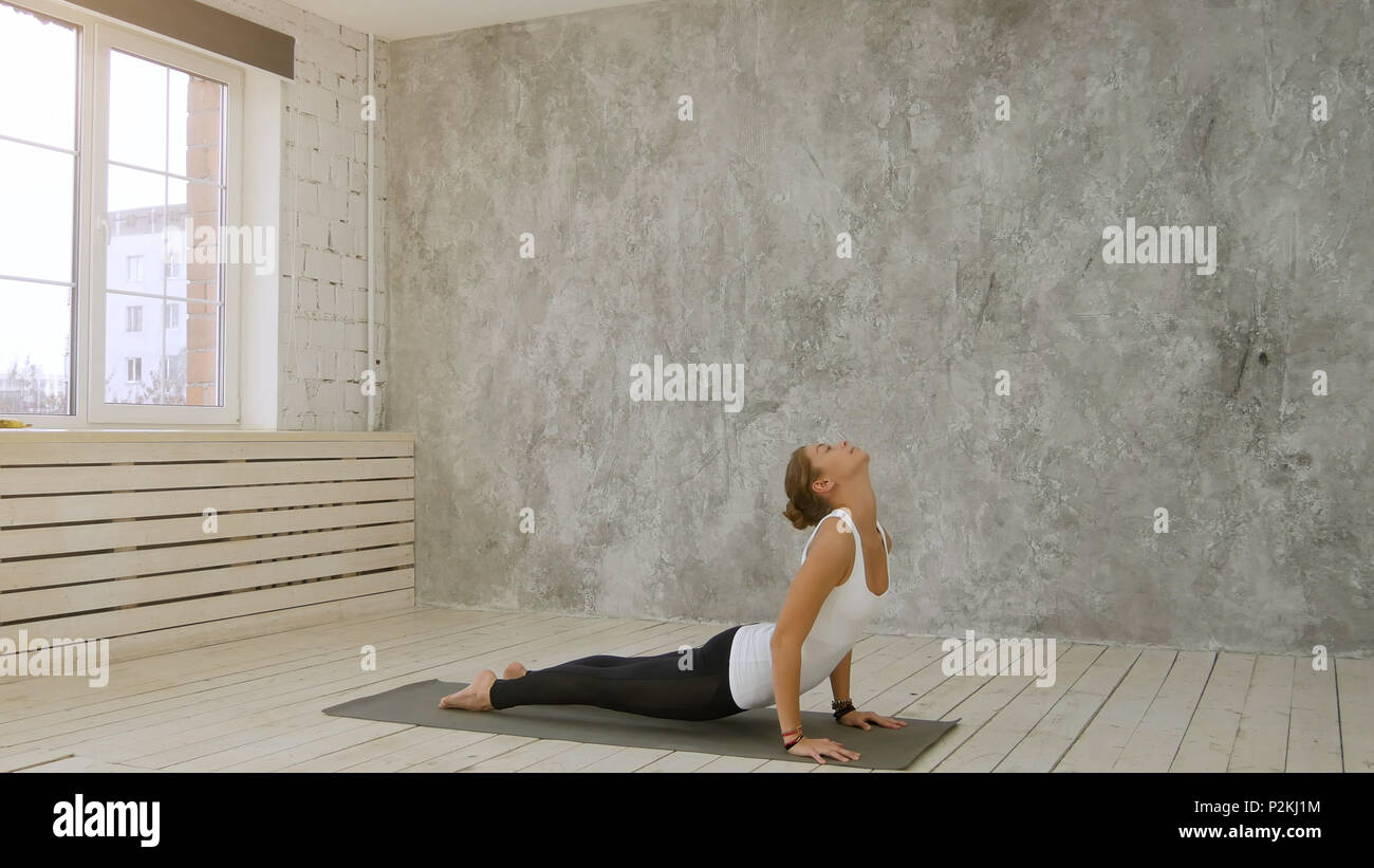 Beautiful sporty fit woman practices yoga asana sun salutation pose ...