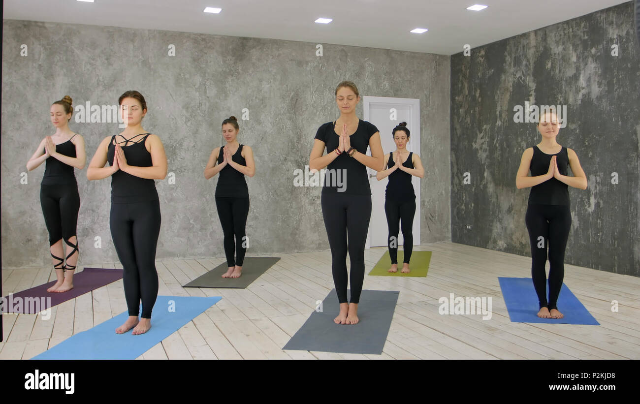 Female trainer with class standing in namaste pose at yoga class Stock ...