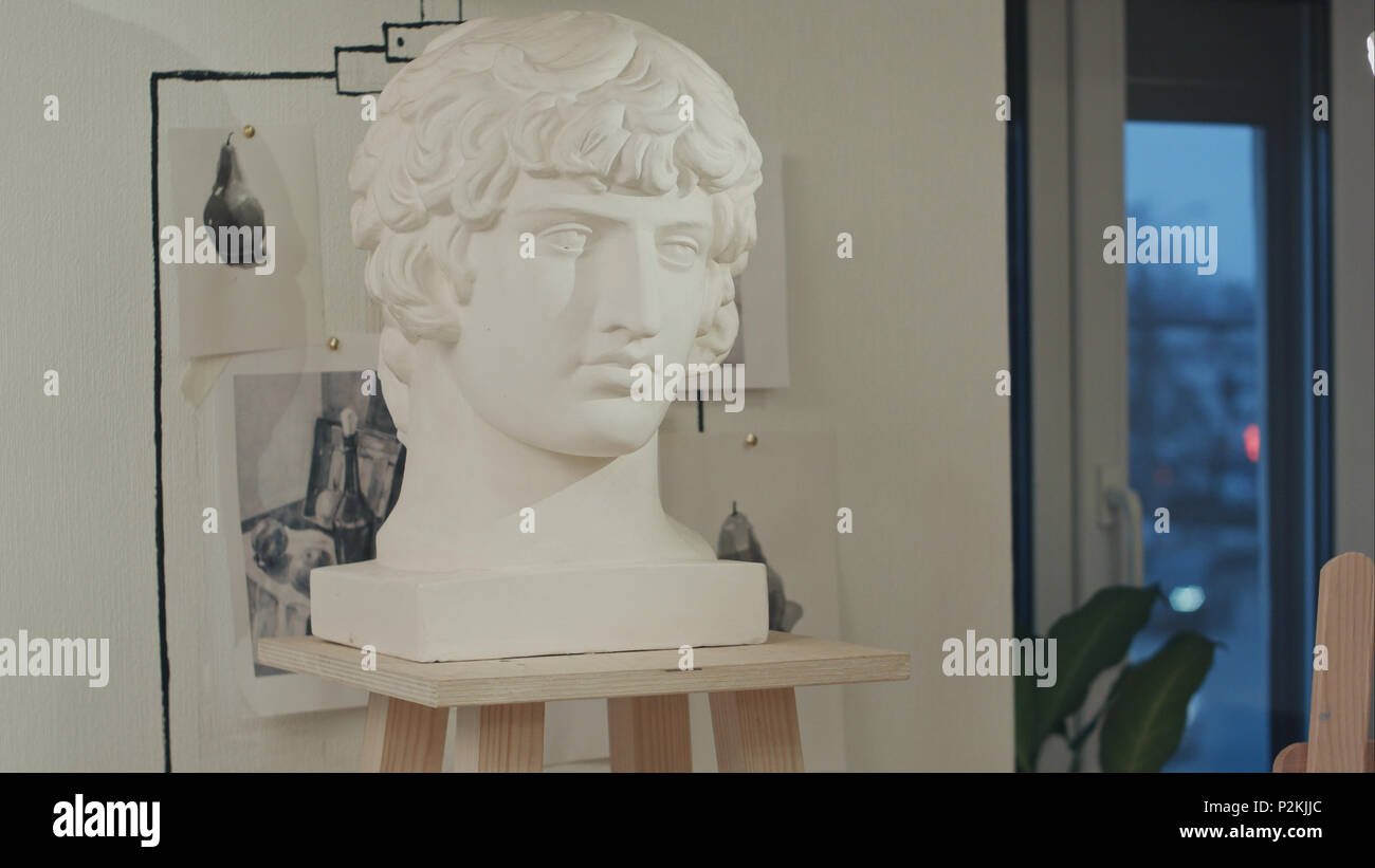 White plaster bust sculpture portrait of a young man in art studio ...