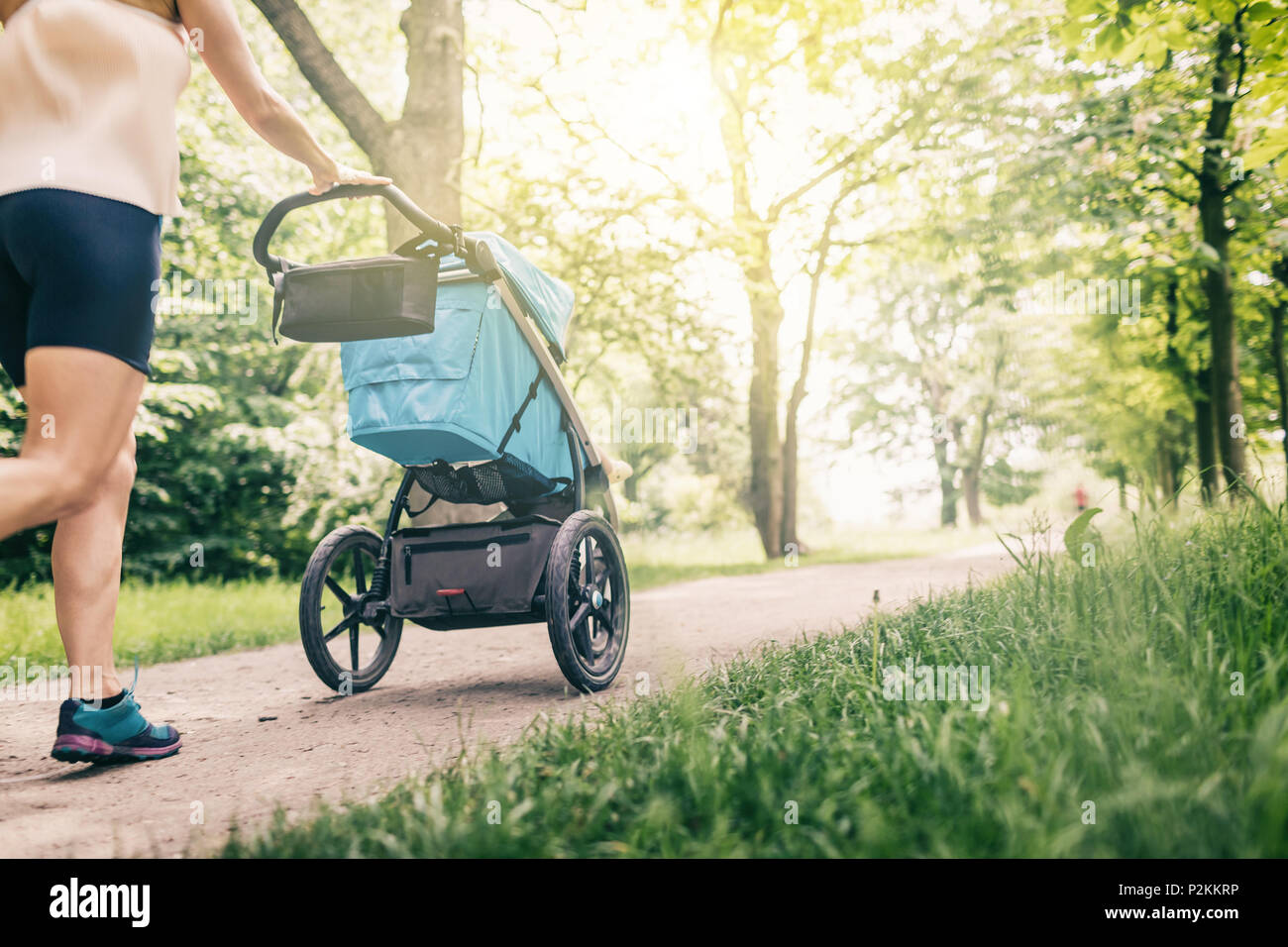 Running woman with baby stroller enjoying summer day in park. Jogging ...