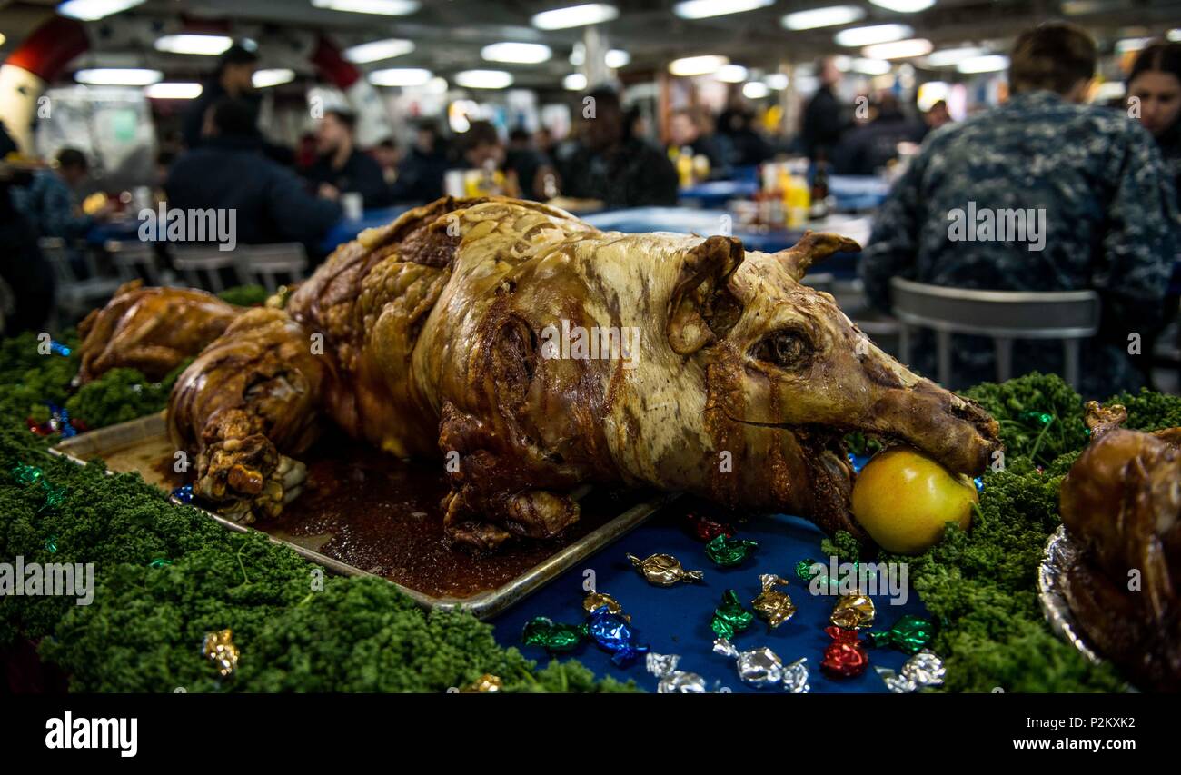 A cooked pig sits on display as Sailors enjoy a Thanksgiving meal with ...