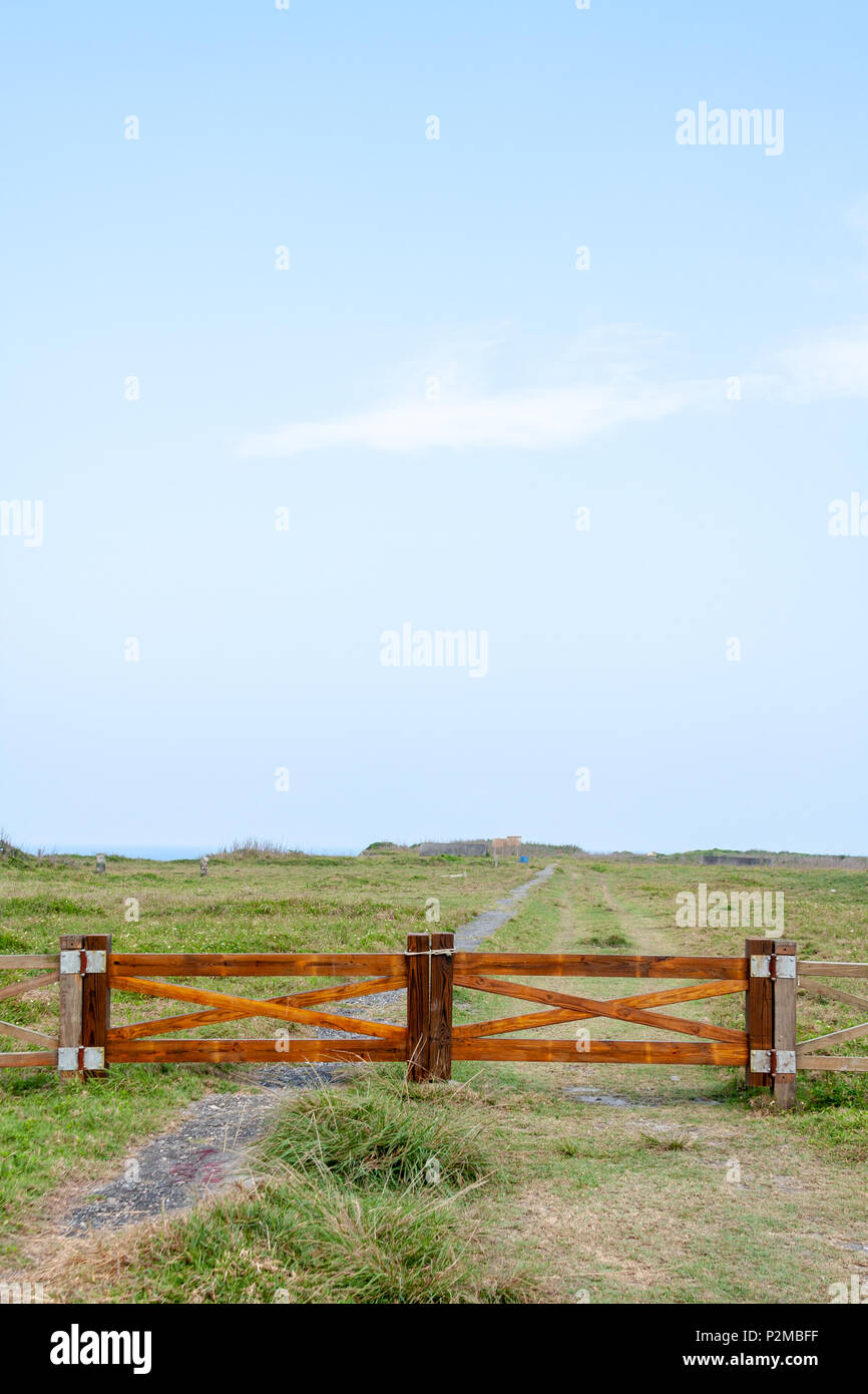 Wooden farm gate and fence on open land. Entrance closed, shut ...