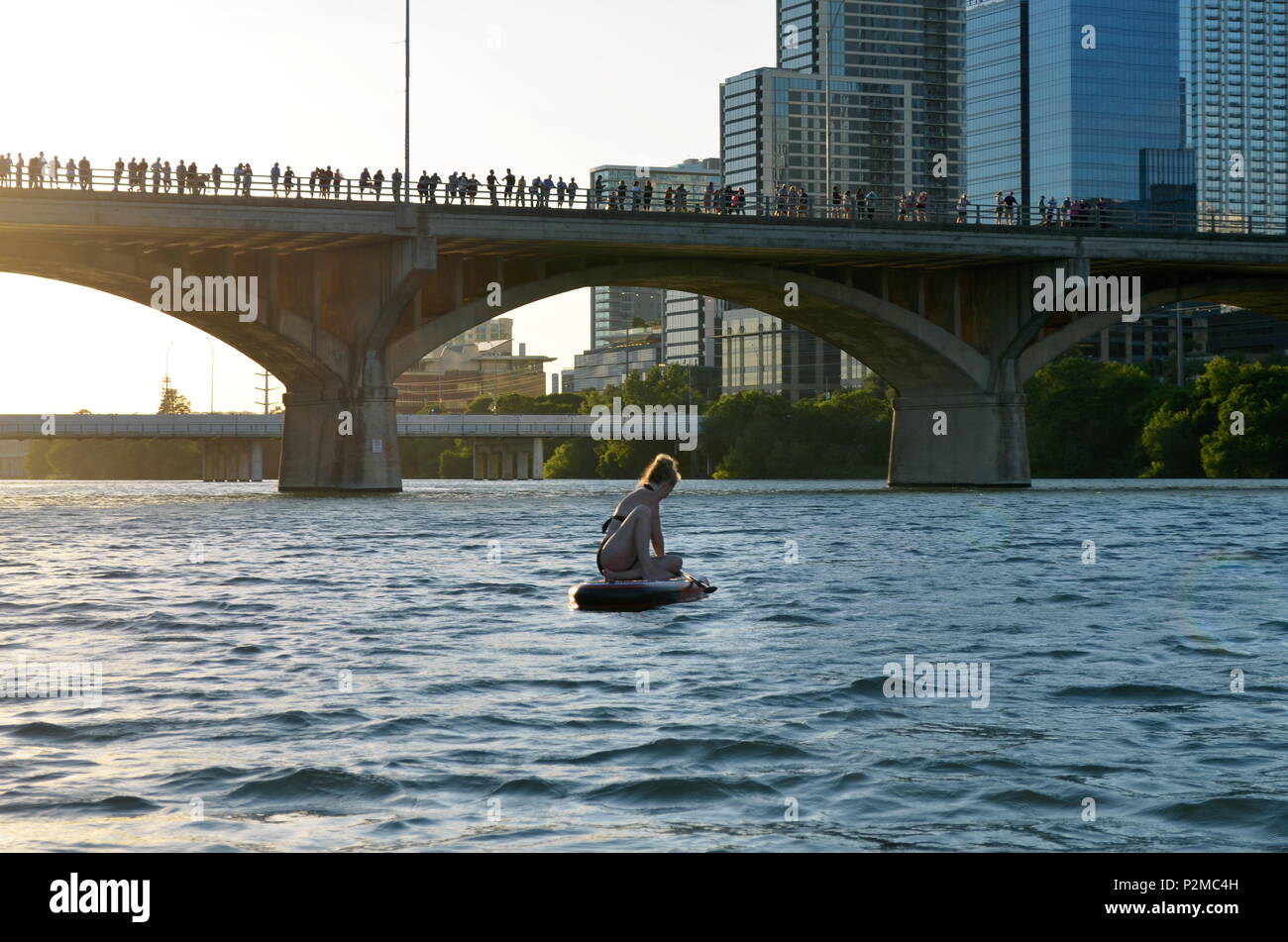 A woman stretches on a paddle board while floating on Ladybird Lake as ...