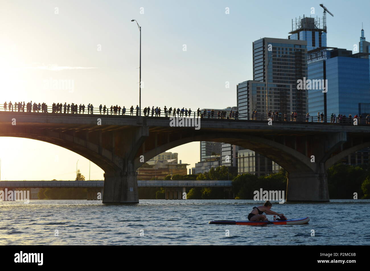 A woman stretches on a paddle board while floating on Ladybird Lake as ...