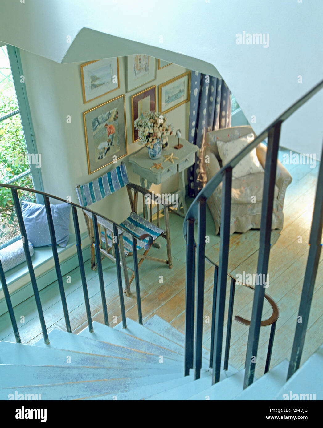Looking down staircase at director's chair and armchair in country hall ...