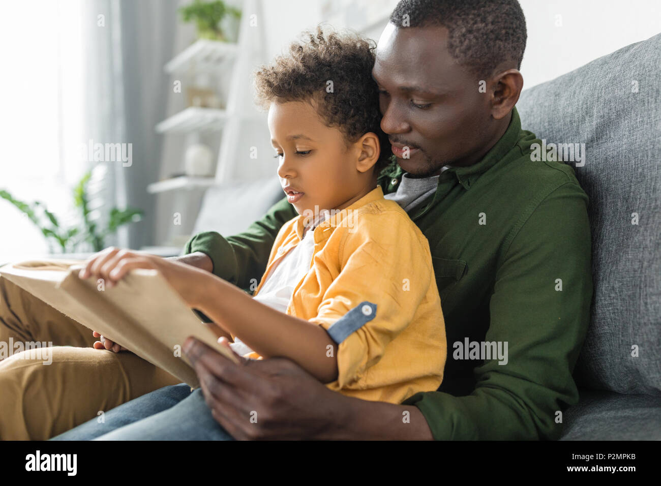 cute african-american father and son reading book together Stock Photo ...