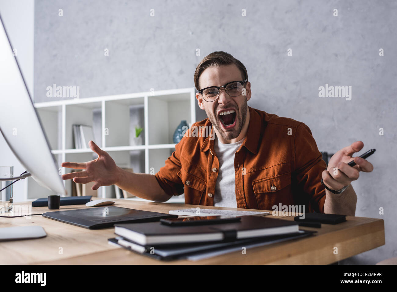 angry designer sitting at workplace and screaming at camera Stock Photo ...
