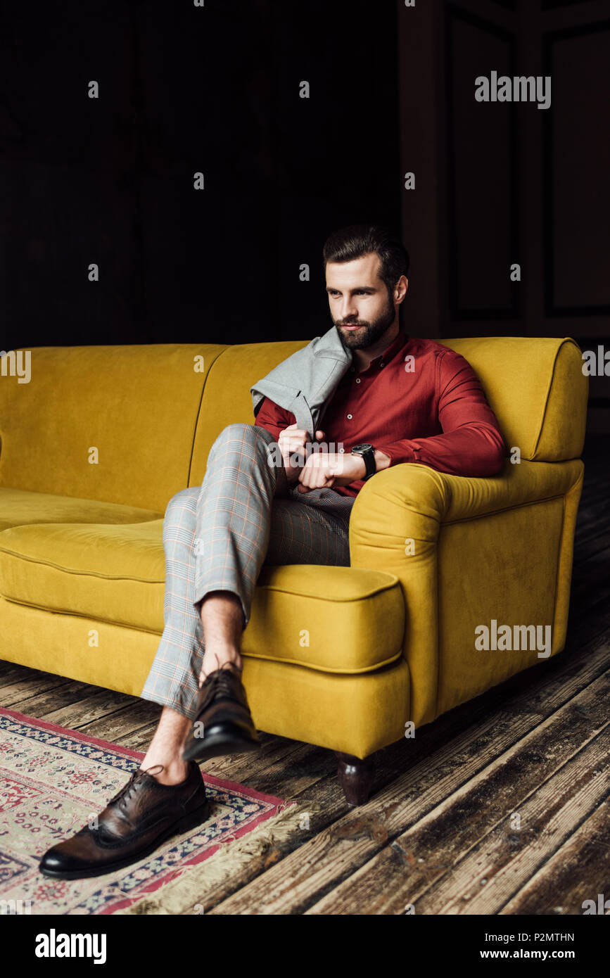 stylish handsome man sitting on yellow sofa Stock Photo - Alamy