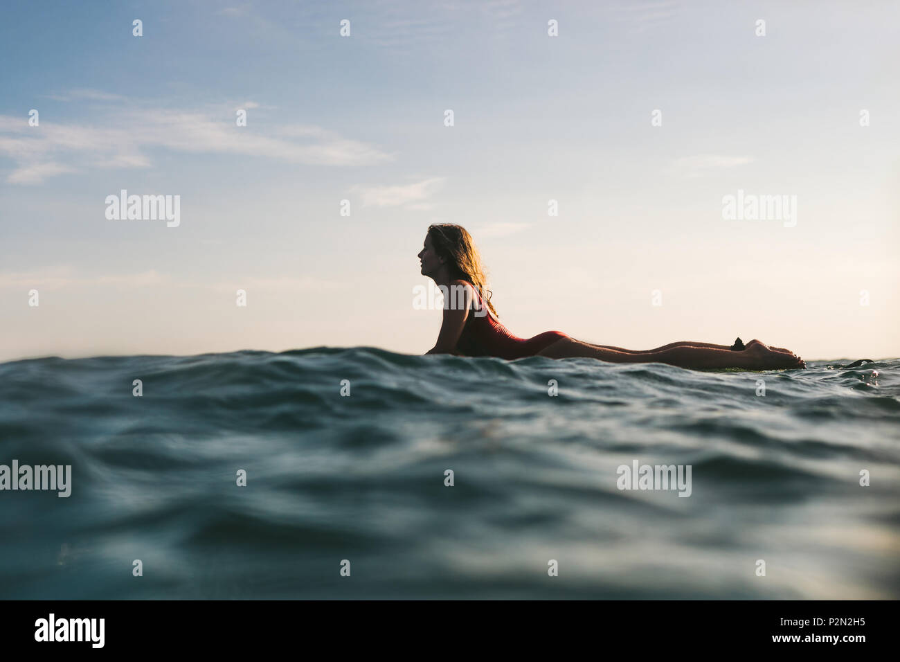 side view of woman in swimming suit surfing alone in ocean Stock Photo ...